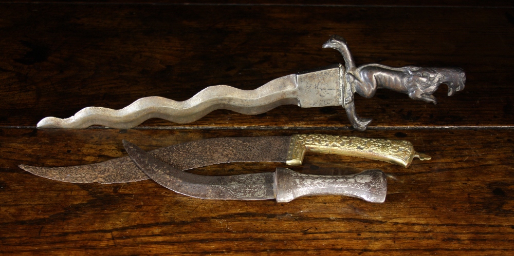 Three Antique Daggers: A serpentine bladed dagger; the handle cast in ...