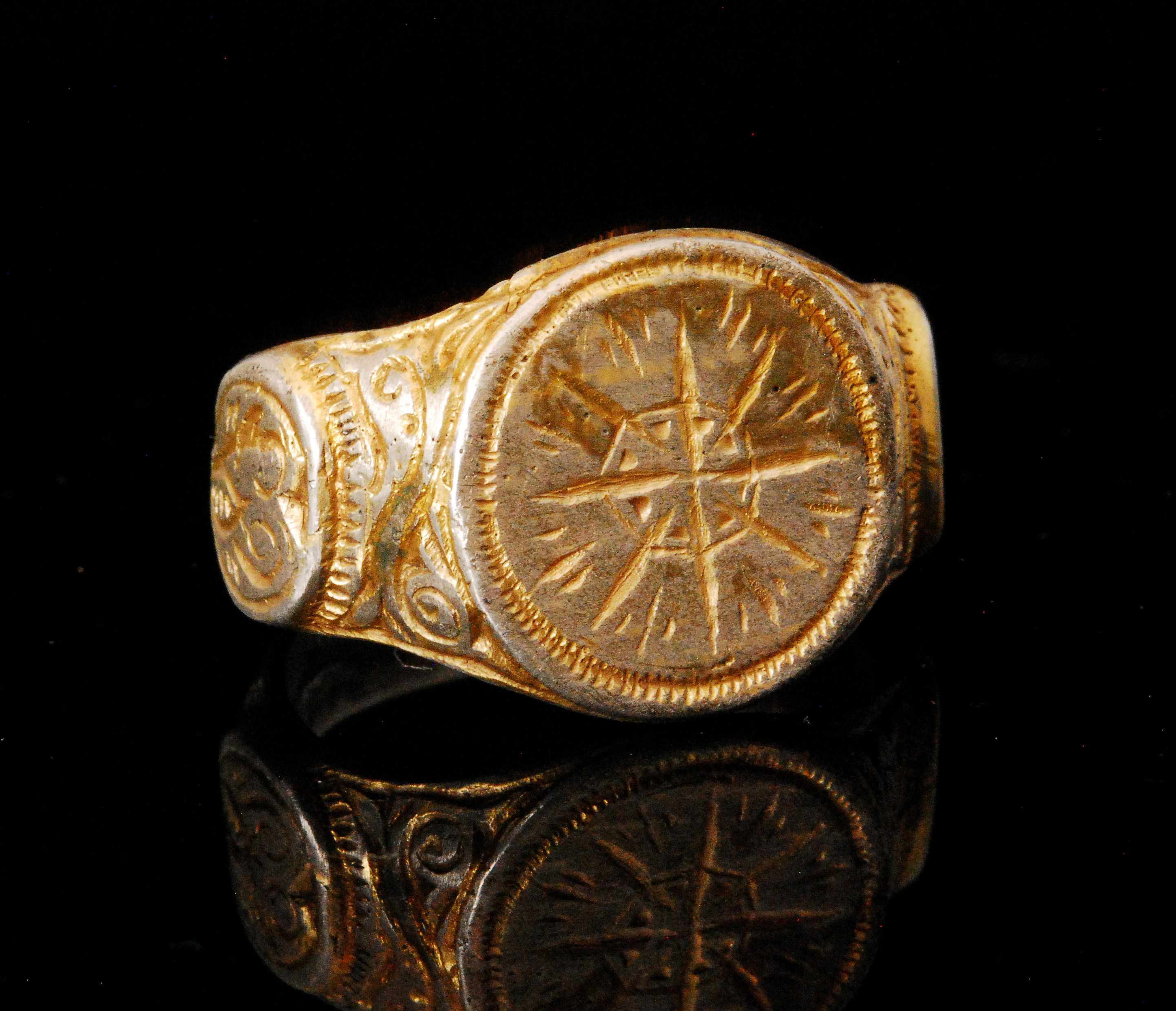 An Anglo-Saxon silver gilt ring, the flat circular centre carved with a compass point design wit
