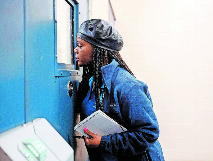 Clinician Erica Shaw speaks with an inmate through a cell door while ...